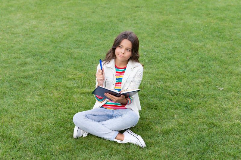 Thoughtful Teen Child Making Notes in Notebook Sitting on Grass. Taking ...