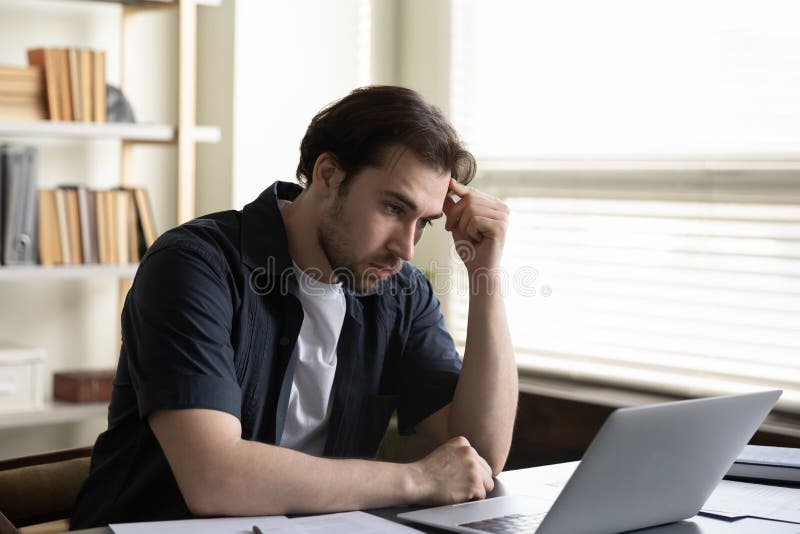Thoughtful Unhappy Young Male Employee Working on Computer. Stock Photo ... Thoughtful Unhappy Young Male Employee Working on Computer. Stock Photo ...
