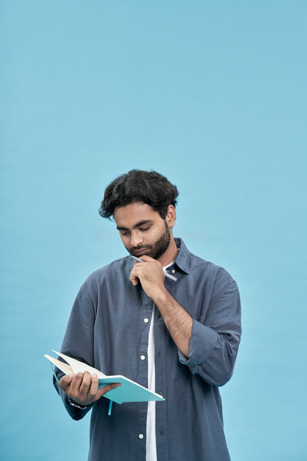 Thoughtful Young Arab Man Student Writing in Notebook Isolated on Blue ... Thoughtful Young Arab Man Student Writing in Notebook Isolated on Blue ...