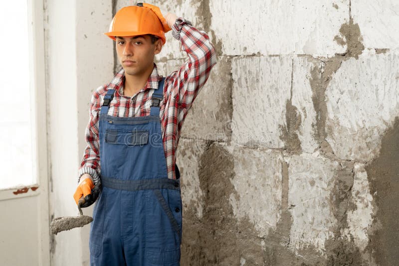 Thoughtful Young Builder with a Spatula on the Background of a Wall of ...