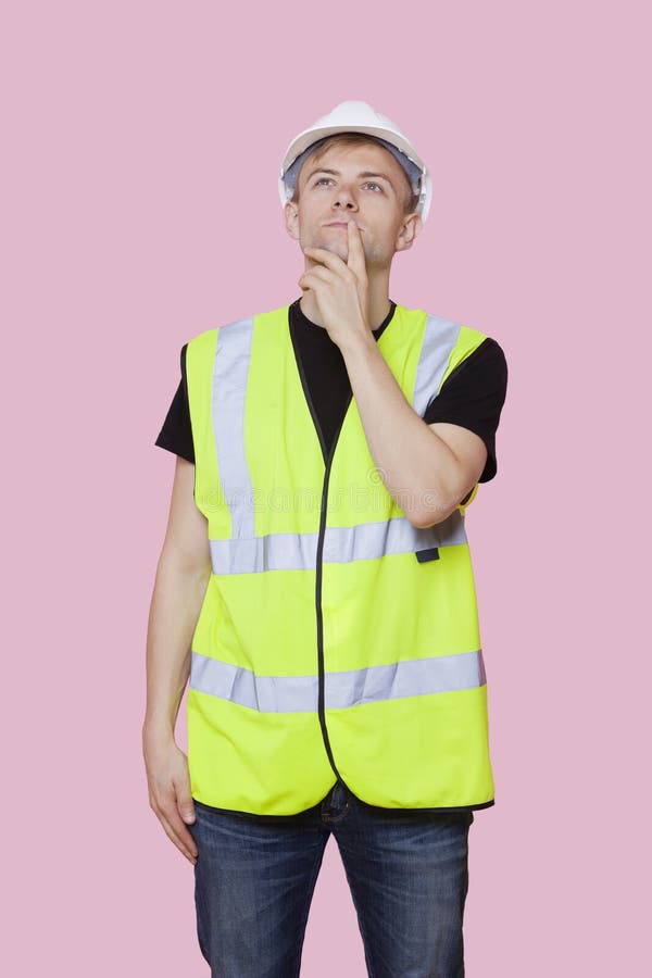 Thoughtful Young Construction Worker Looking Away Over Pink Background ...