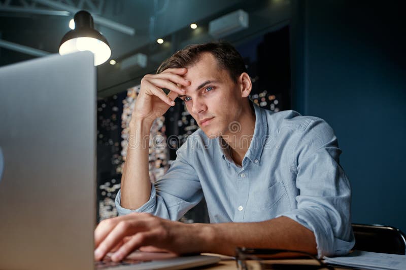 Thoughtful Young Man Looking at a Laptop Screen . Stock Photo - Image ...