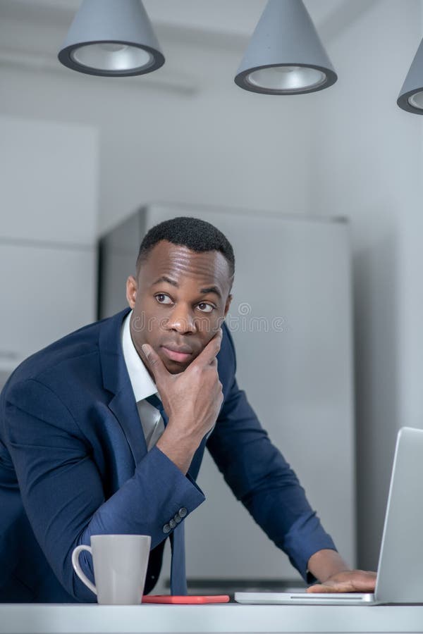 Elegant Dark-skinned Man Reading Something on Laptop and Looking ...