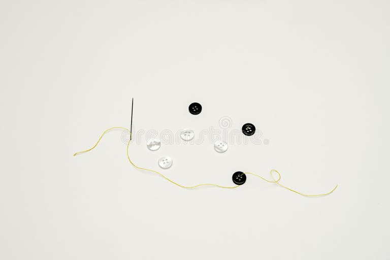 Thread of Yellow Color with a Threaded Needle, Black and White Buttons ...