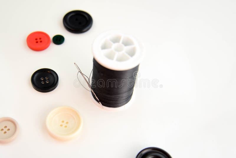 Threaded Needle, Black Thread Spool and Buttons Stock Photo - Image of ...