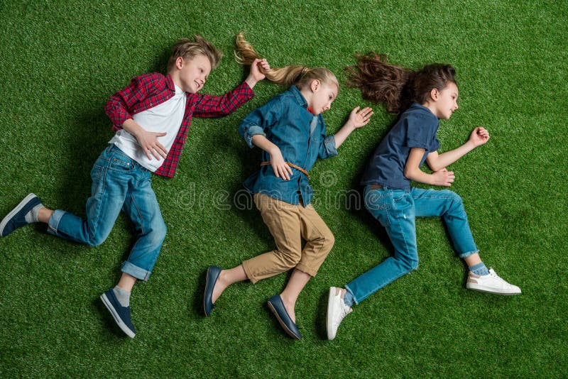 Three Adorable Children Lying Together on Green Lawn Stock Photo ...