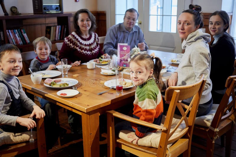 Three Adults and Four Children Sit at Wooden Table Stock Photo - Image ...