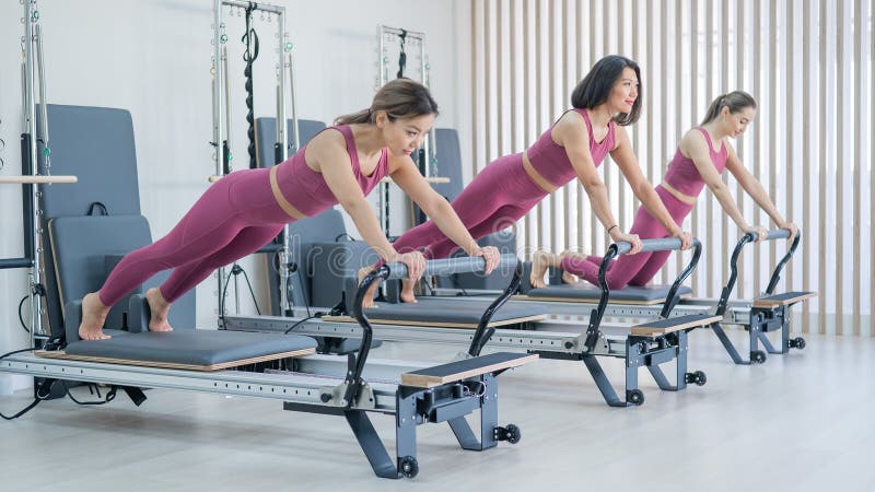 Three Asian Women Doing Plank on Reformer Machine. Stock Image - Image ...