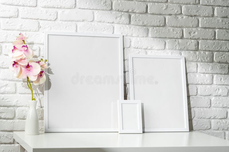 Three Blank Photo Frames on a White Table Against a Brick Wall ...