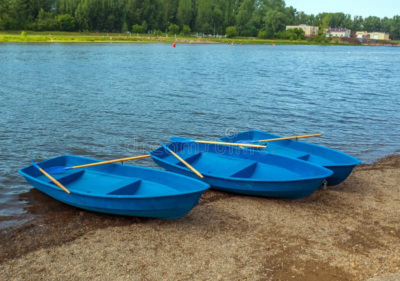 Three Blue Plastic Boats with Oars Pulled Ashore Stock Image - Image of ...