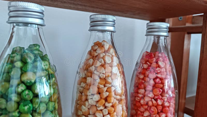 Three Bottles of Different Colored Corn Kernels are on a Shelf Stock ...