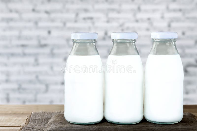 Three Bottles of Milk on a Wooden Table and White Concrete Wall ...