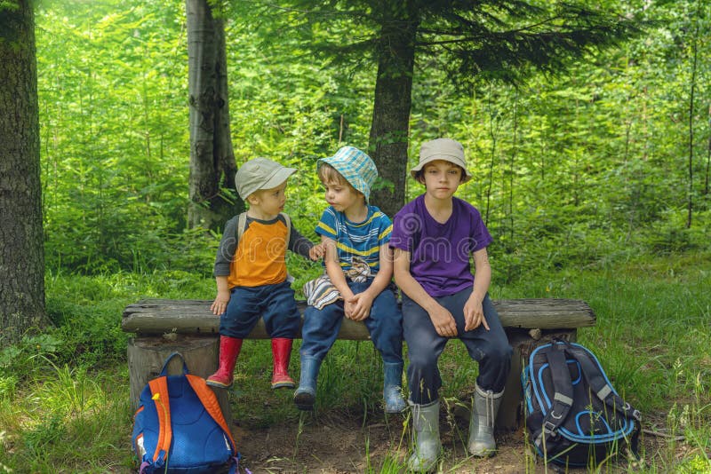 Three Boys are Sitting on a Bench. they Rest during the Journey Stock ...