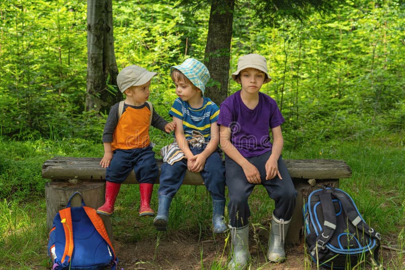 Three Boys are Sitting on a Bench. they Rest during the Journey Stock ...