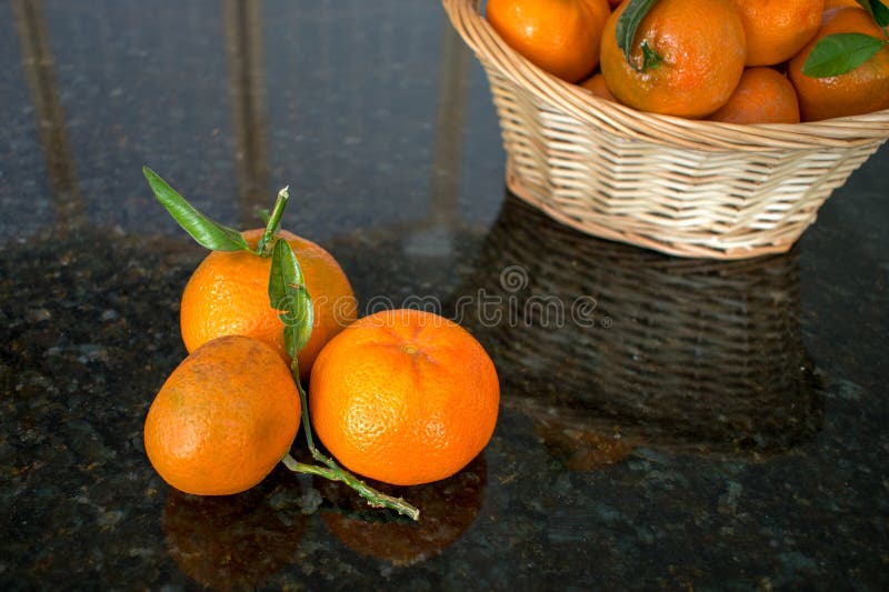 Three Mandarin Oranges in Front of Wicker Basket on Black Granite Stock ...