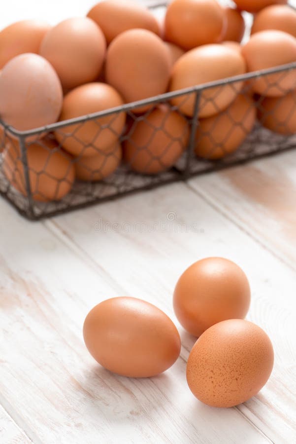 Three Brown Eggs with Mesh Tray of Eggs on Background Stock Photo ...