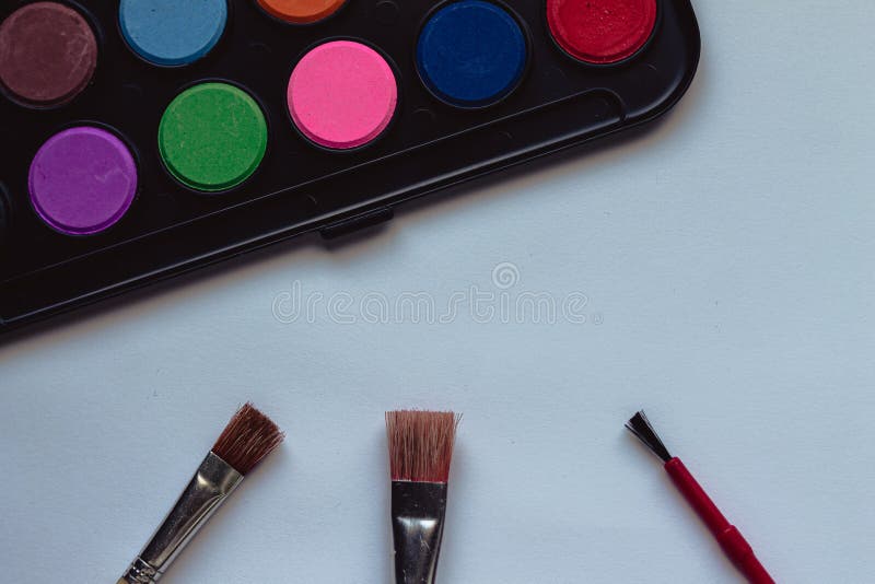 Three Brushes Next To a Palette of Watercolors of Different Colors ...