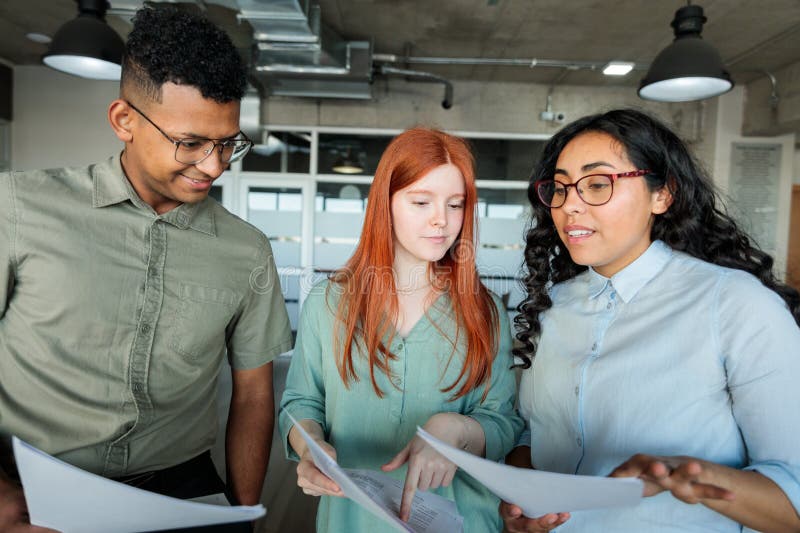 Three Business Office Colleagues Reviewing Important Documents Standing ...