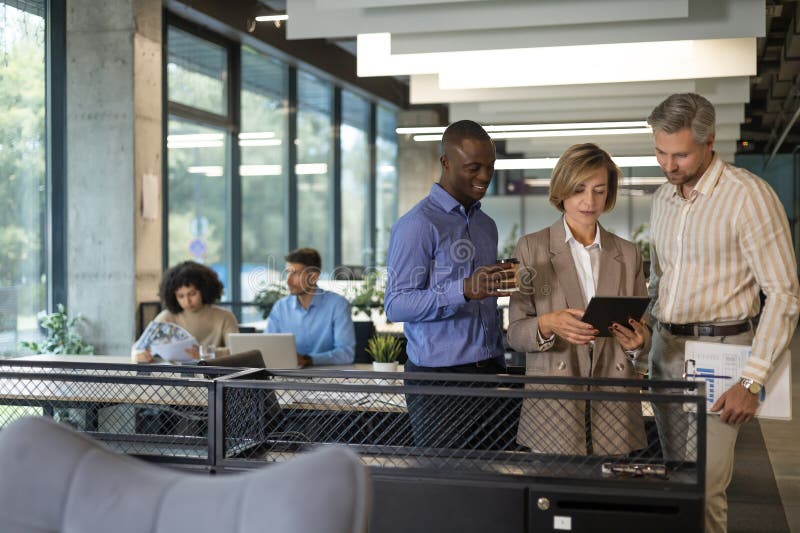 Three Business People Discussing Work Together Using a Tablet in a Modern Office Stock Photo ...