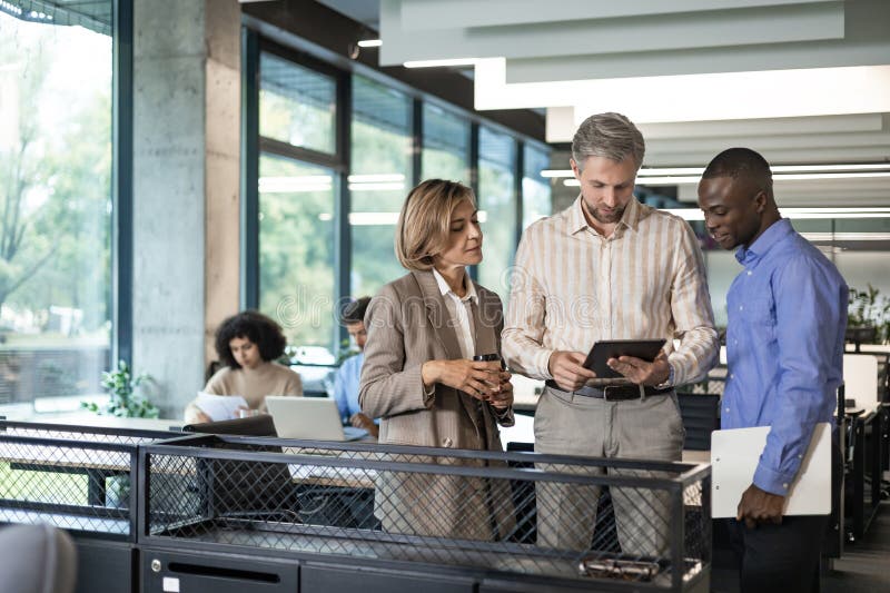 Three Business People Discussing Work Together Using a Tablet in a ...