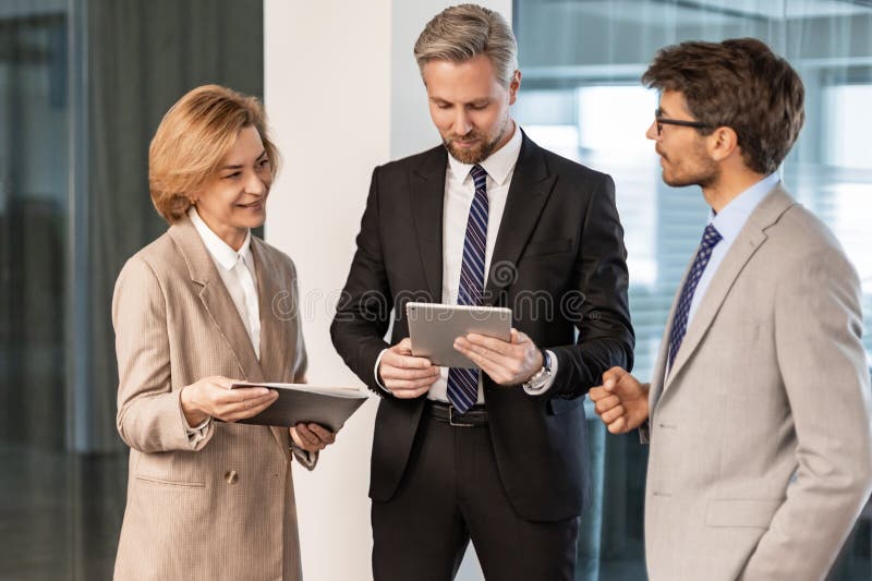 Three Business People Discussing Work Together Using a Tablet in a Modern Office Stock Photo ...