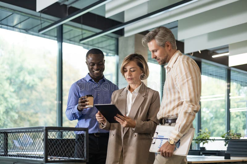 Three Business People Discussing Work Together Using a Tablet in a ...
