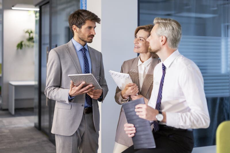 Three Business People Discussing Work Together Using a Tablet in a ...