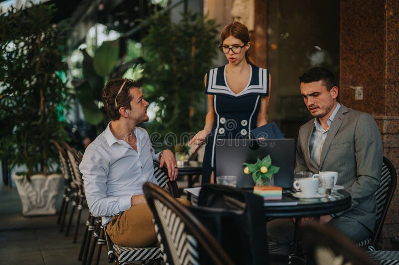 Businesspeople Having a Meeting at an Outdoor Cafe with Laptops and ...