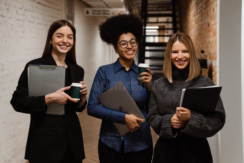 Three Business Women Smiling at Camera while Standing in Coworking ... Three Business Women Smiling at Camera while Standing in Coworking ...