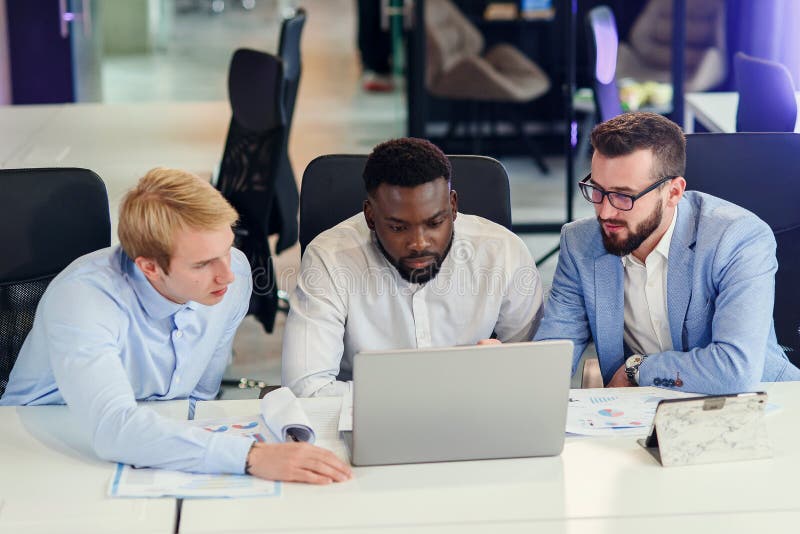 Three Businessmen Sitting at the Modern Office Tables and Analysing ... Three Businessmen Sitting at the Modern Office Tables and Analysing ...