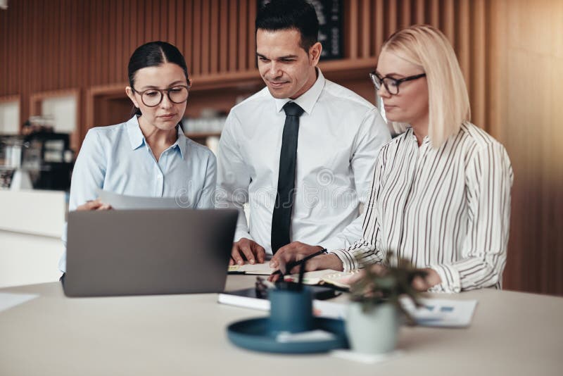Three Businesspeople Standing at an Office Table Going Over Note Stock ...