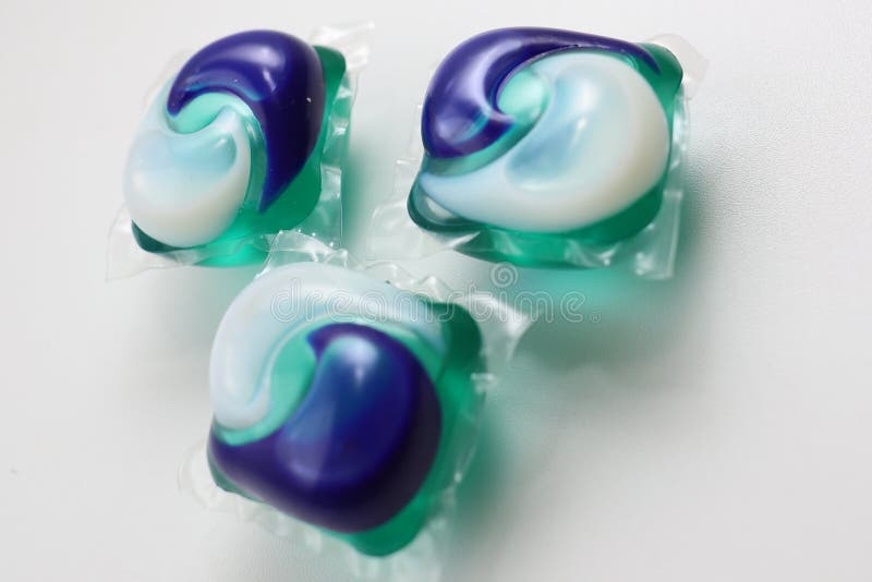 Three Capsules of Blue and Green Powder, a Liquid Detergent Stock Photo ...