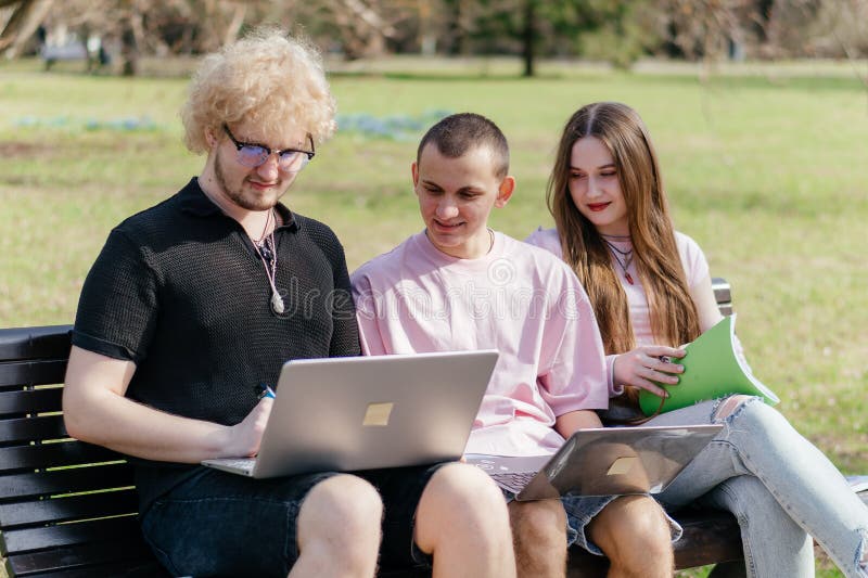 Three Cheerful Students Study and Work Together Outdoors on a Sunny Day ...