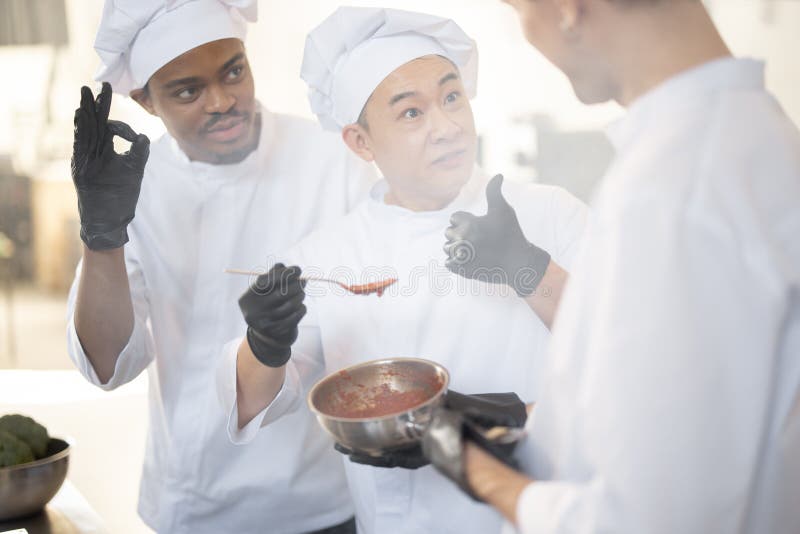 Chef Cooks Tasting Sauce with a Spoon while Cooking in the Kitchen ...