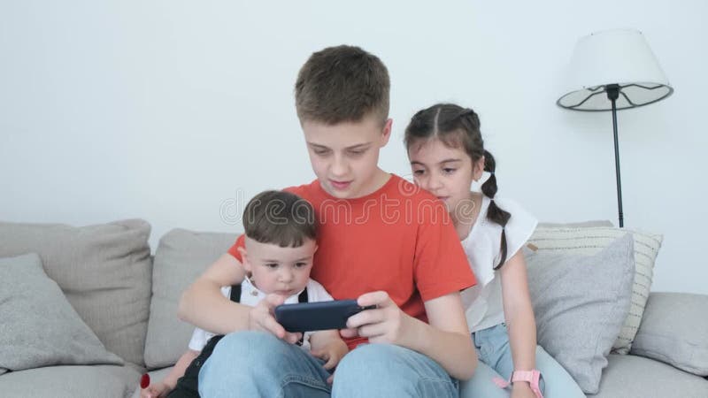 Three Children of Different Ages are Using a Smartphone while Sitting ...