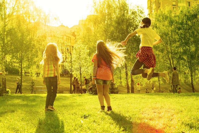 Three Children Girls at Sunset Jumping in the Park, Back View Stock ...