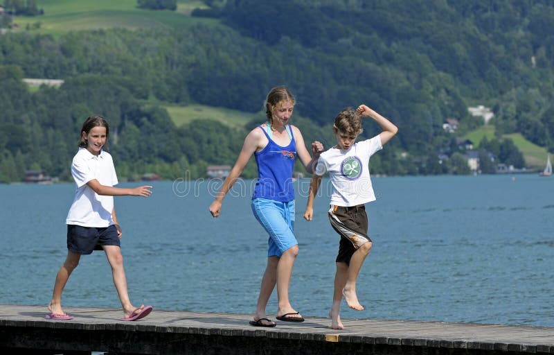 Three Children Marching Along A Pier Stock Photo - Image of kids ...