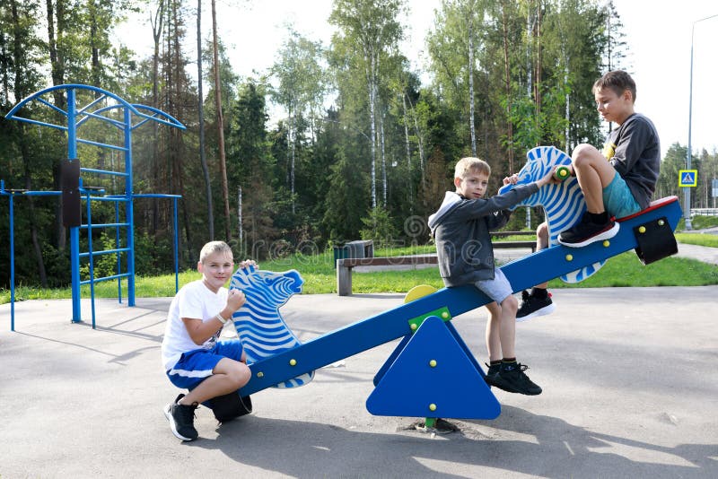 Three Children Playing Seesaw in Playground Stock Photo - Image of ...
