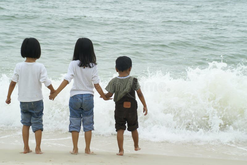 Three Children Playing with Waves Stock Photo - Image of waves, trio ...