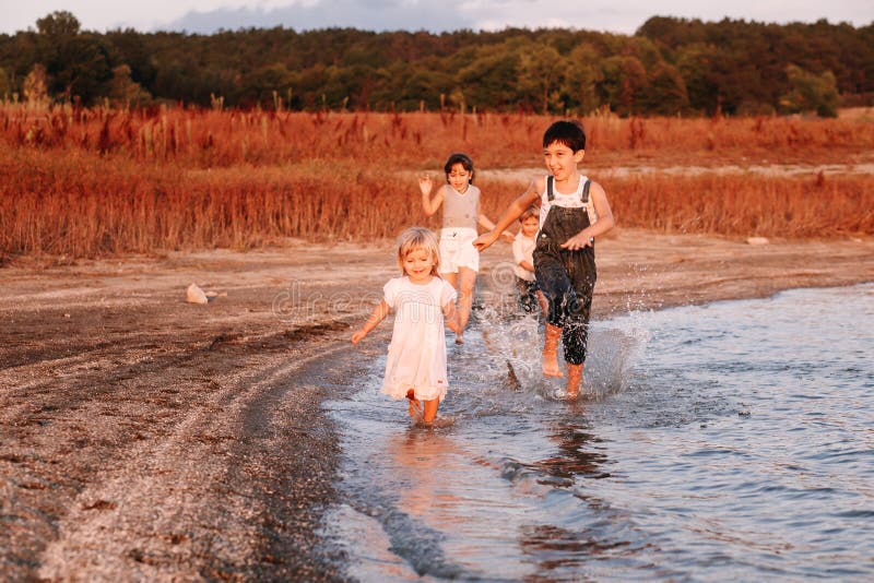 Three Children Running Along Beach Stock Photo - Image of shorts, group ...