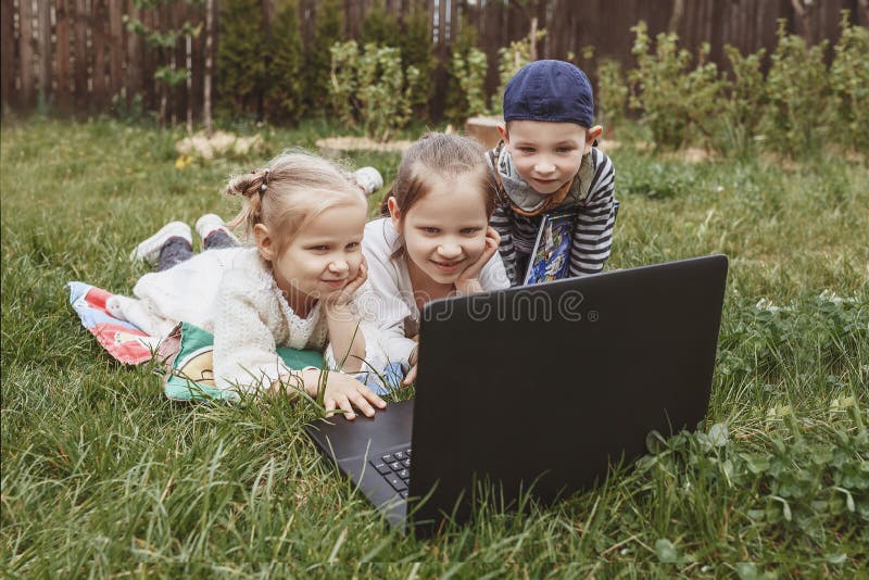 Kids Playing Computer Games Lying on the Grass Stock Image - Image of ...