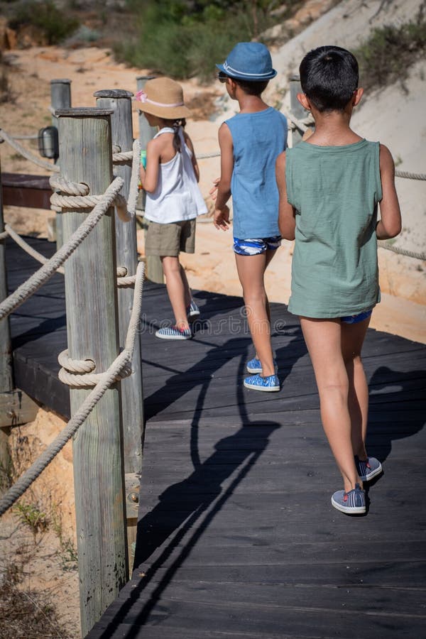 Three Children on a Walkway on the Beach. Stock Photo - Image of ...