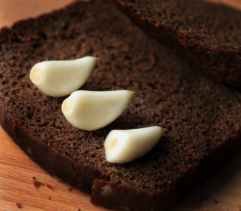 Three Cloves of Garlic on Brown Bread Stock Photo - Image of condiment ...