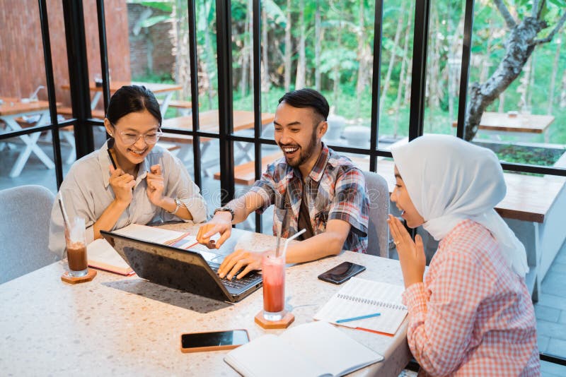 Three College Students Smiling Happily Looking at a Laptop Stock Photo ...