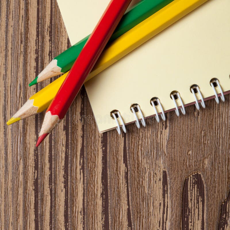 Three Colored Pencils and Notebook on Wooden Table. Stock Image - Image ...