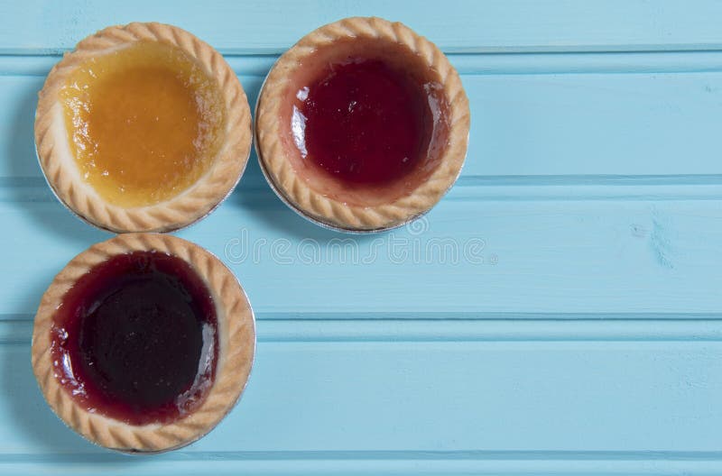 Three Colourful Jam Tarts on a Blue Background Stock Image - Image of ...