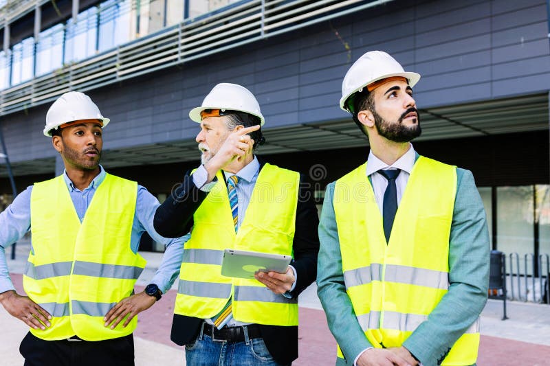 Three Construction Engineers Having a Discussion on Building Site ...