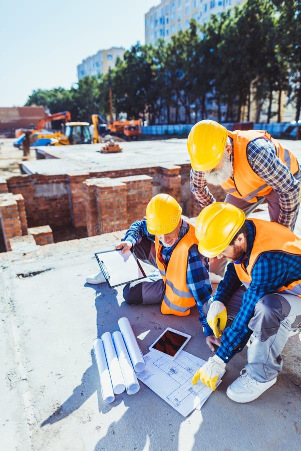 Three Construction Workers Sitting on Concrete at Construction Site ...