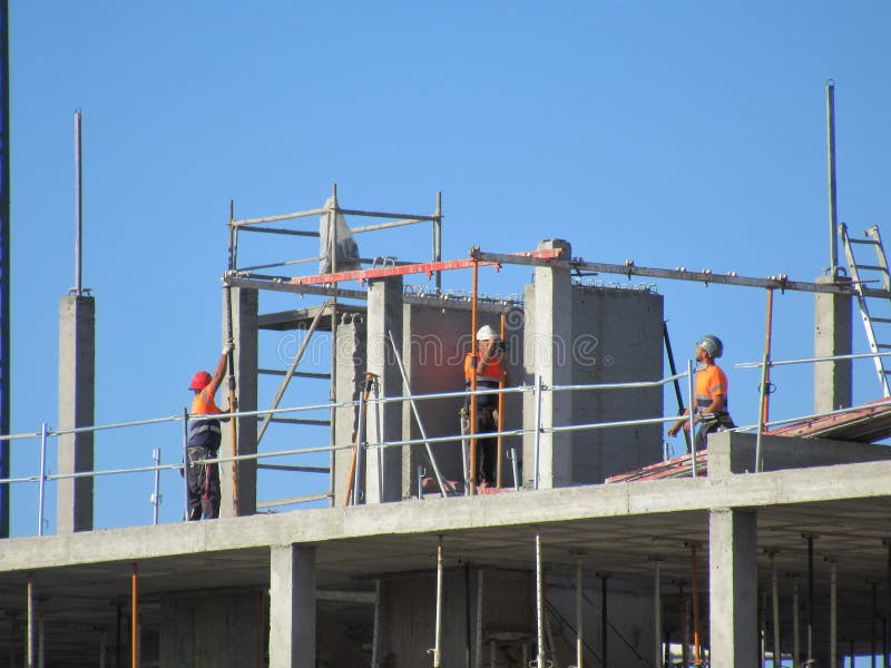 Three Construction Workers Working on a Construction Site. Bricklayer ...