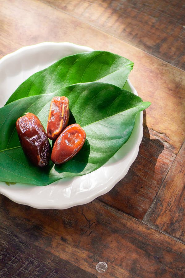 Three Dates in a White Plate with a Leaf on a Wooden Table Stock Photo ...